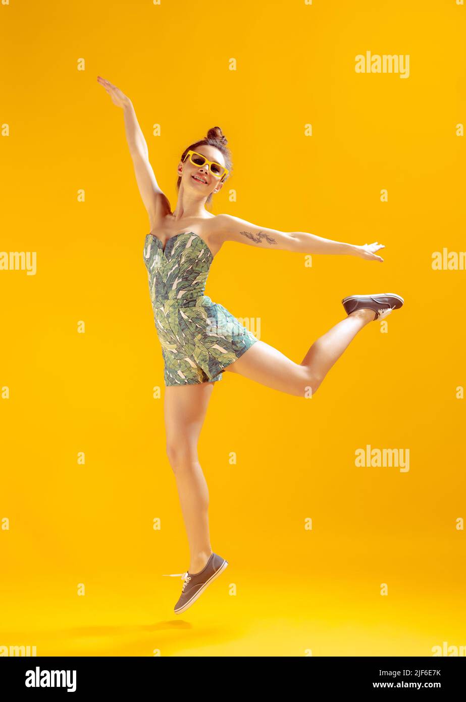 Full-length portrait of beautiful young girl posing, cheerfully jumping ...