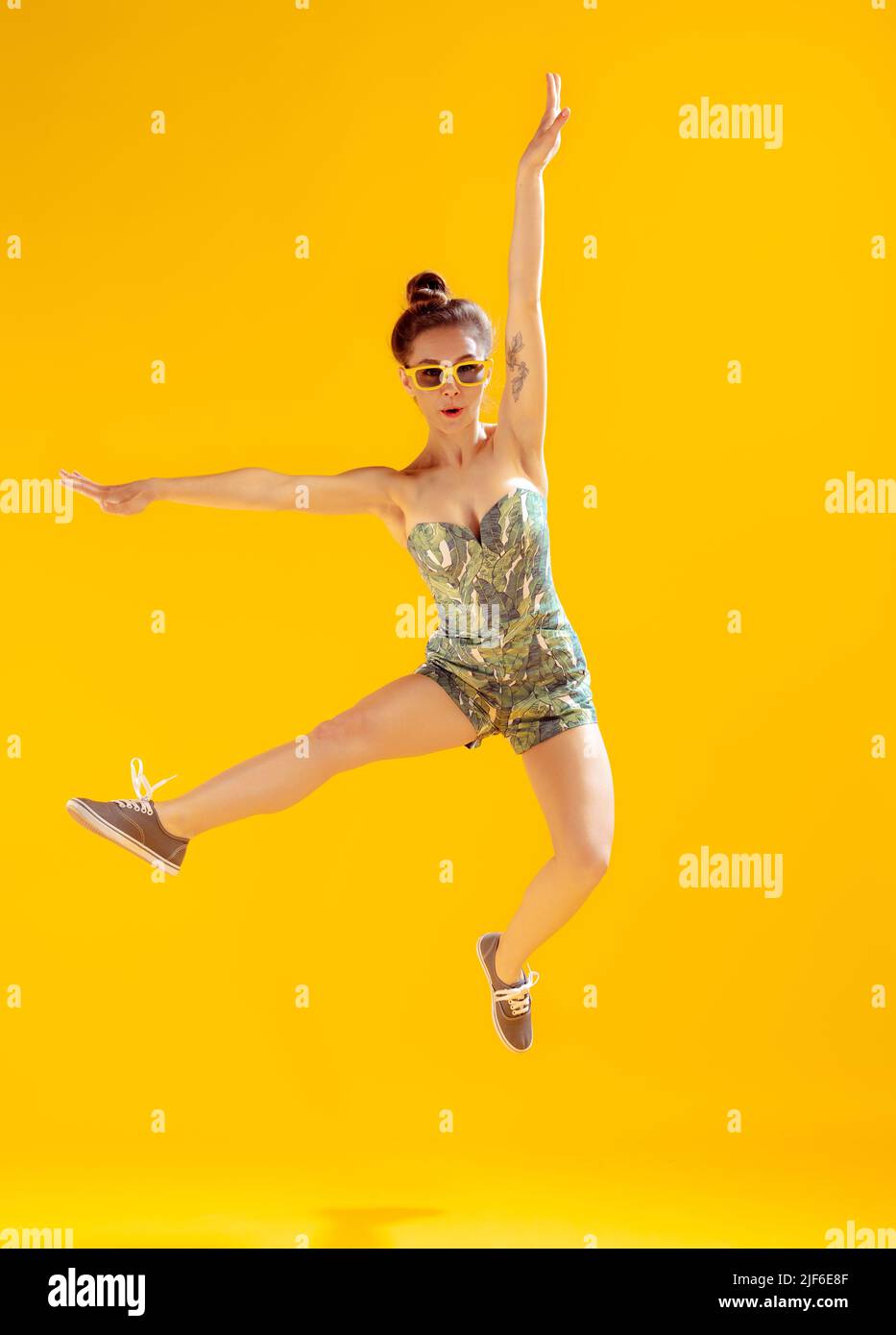 Full-length portrait of beautiful young girl posing, cheerfully jumping ...