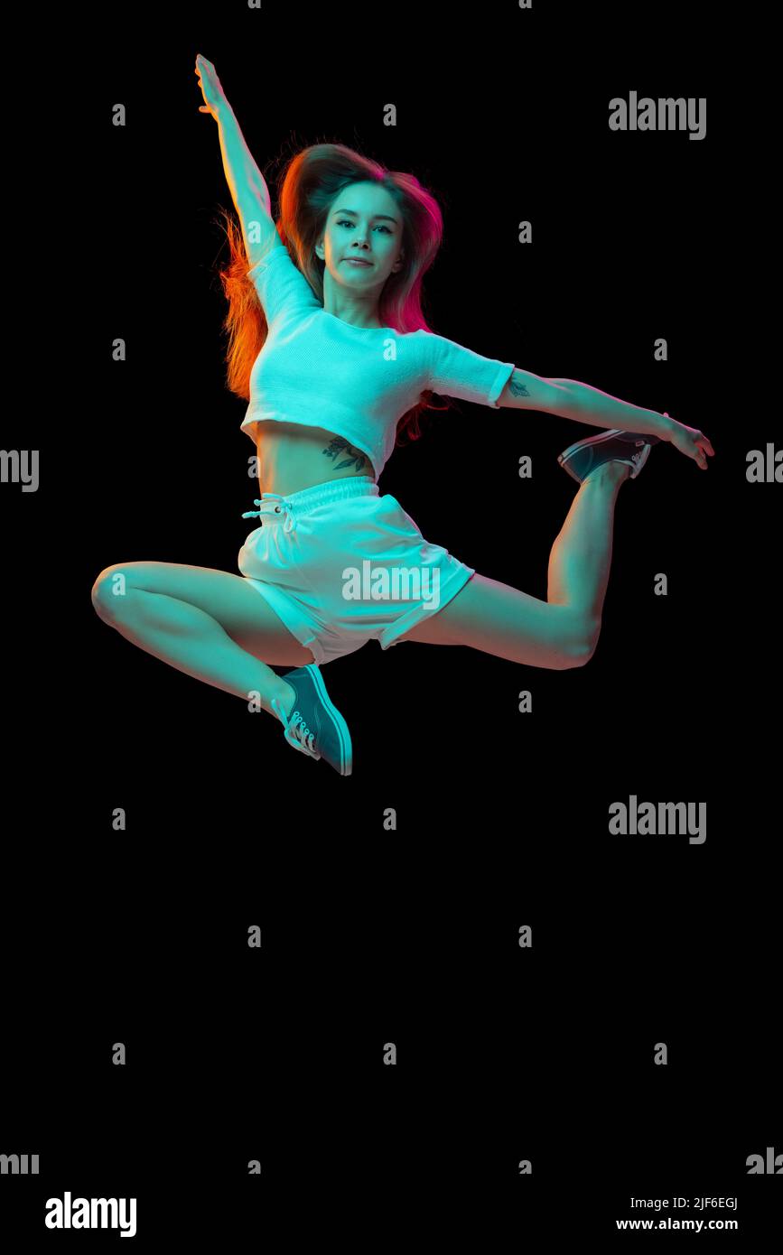 Full-length portrait of young cheerful girl posing, jumping isolated ...
