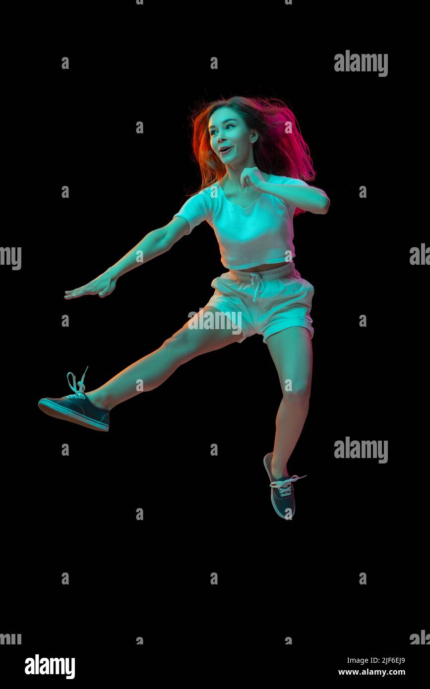 Full-length portrait of young cheerful girl posing, jumping isolated ...
