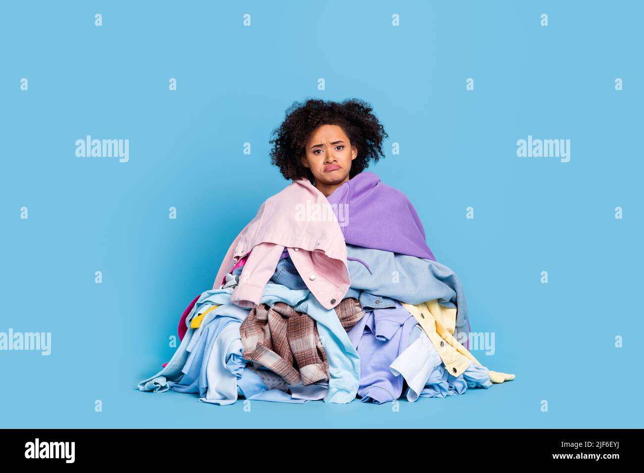 Photo of stressed depressed young woman covered big stack clothes ...