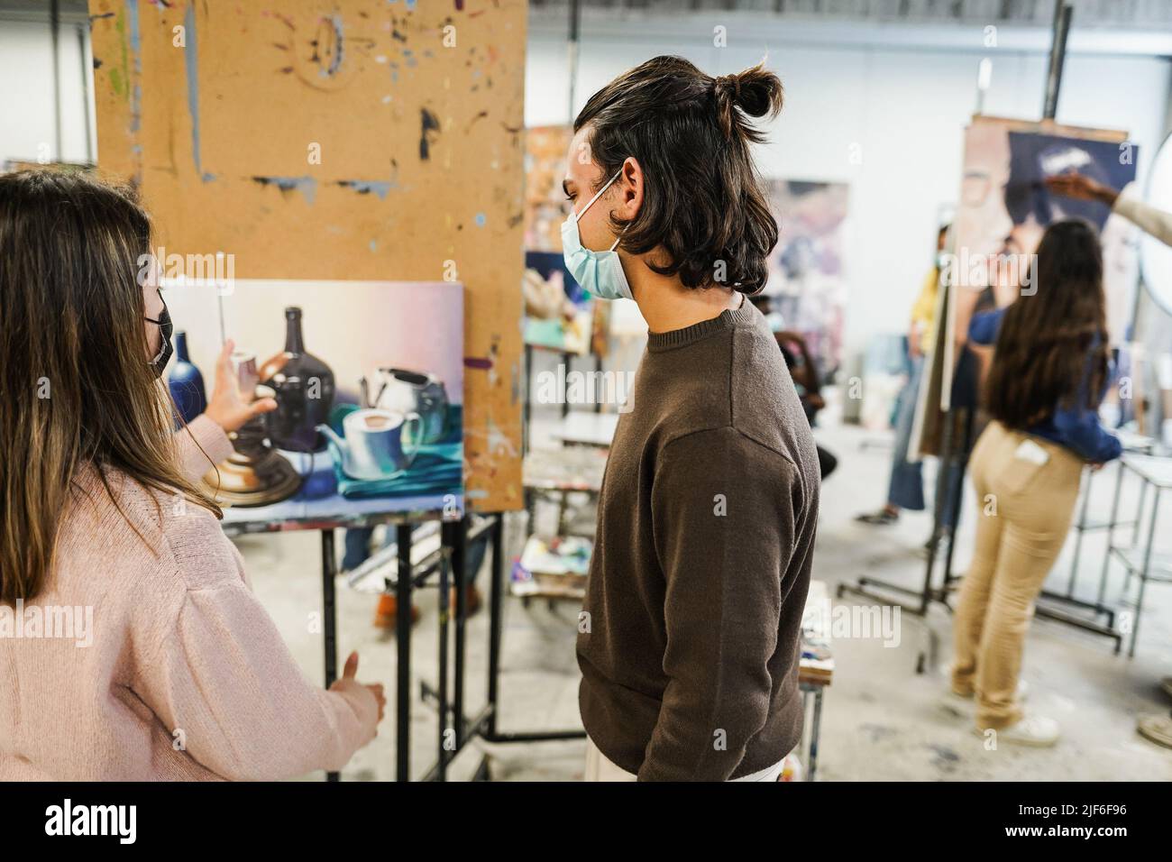 Young students painting inside art room class at college - Main focus ...