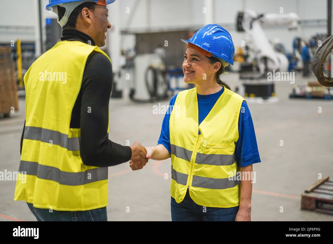 Engineer workers shaking hands inside robotic factory - Focus on senior ...