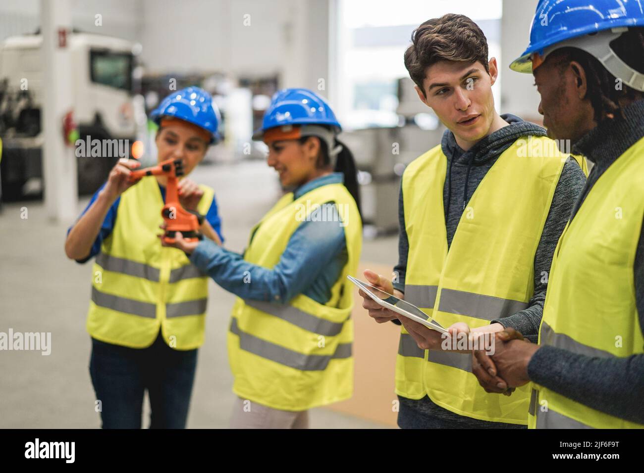 Multiracial engineers working inside robotic factory - Focus on young ...