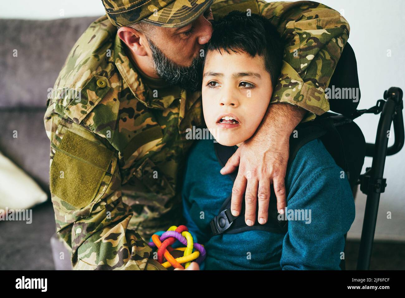 Military soldier hugging his son with disability at home - Focus on kid ...