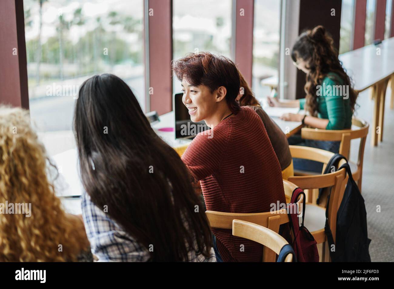 Young multiracial group of students studying inside university library ...