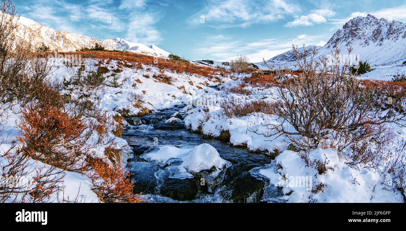 A frozen river in the middle of a mountainous field covered in snow and ...