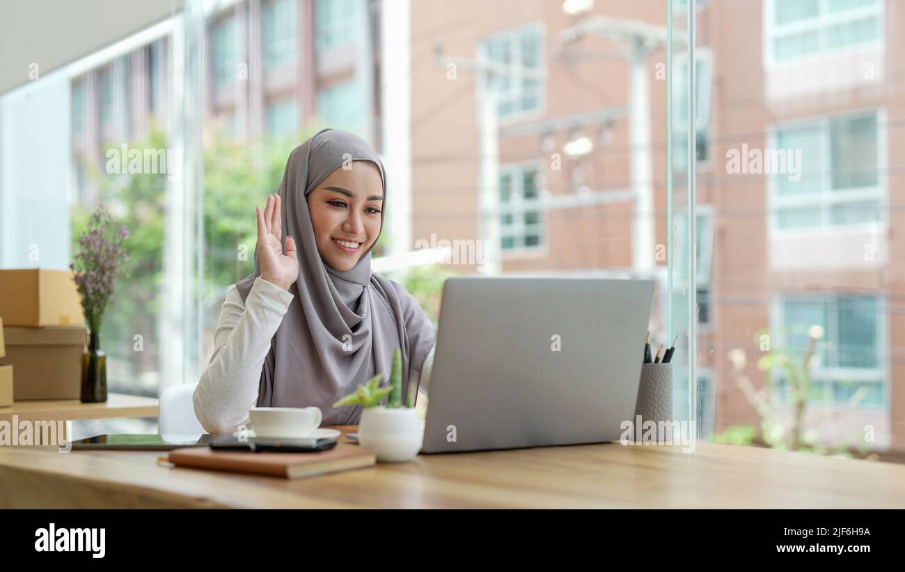 Young smiling beautiful muslim woman using laptop computer working and ...