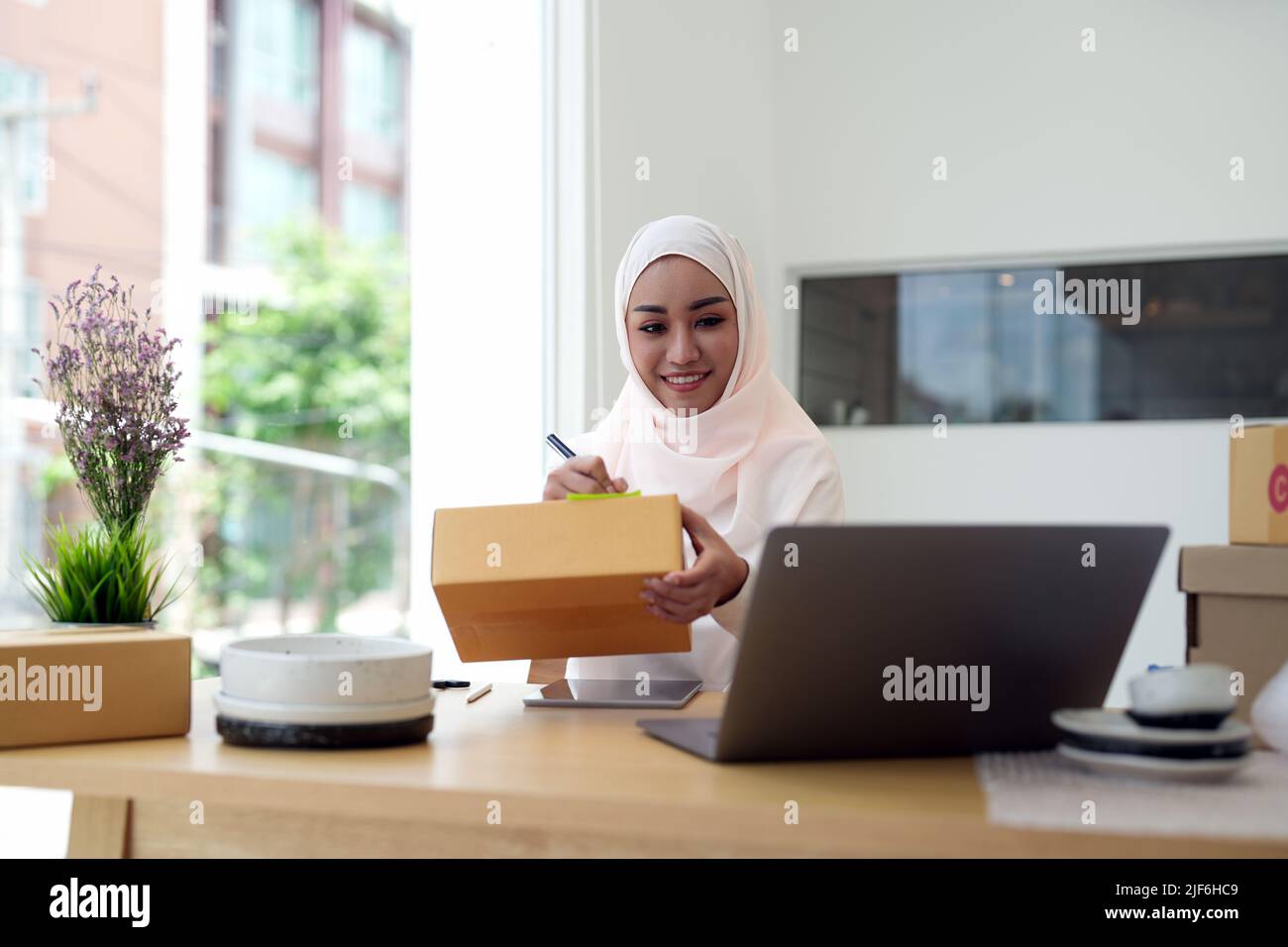 Happy young muslim woman owner writing address on cardboard box, Young ...