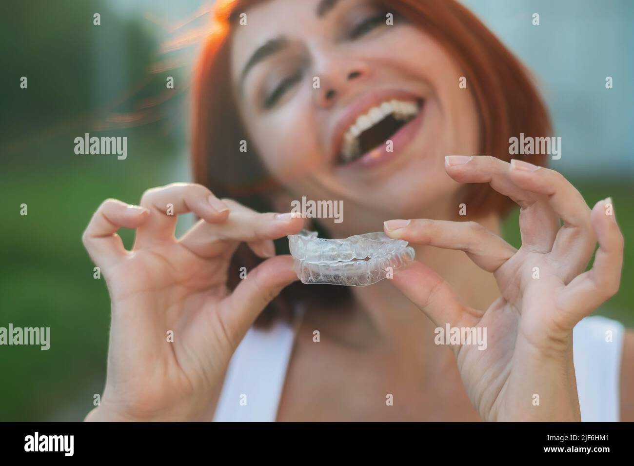 Red-haired Caucasian woman holding transparent mouthguards for bite ...