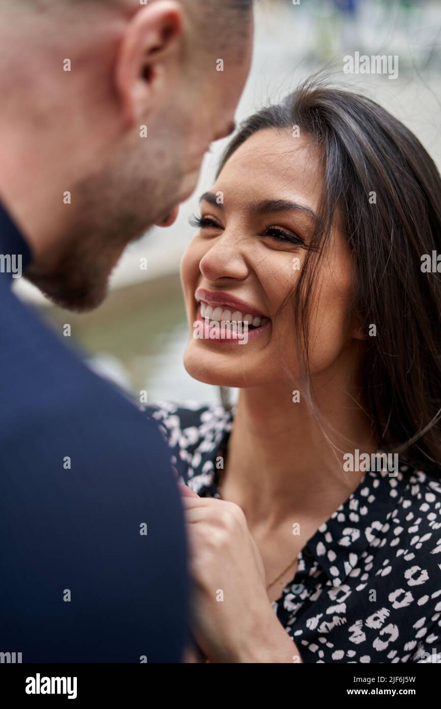 Positive couple in outerwear caressing while standing looking at each ...
