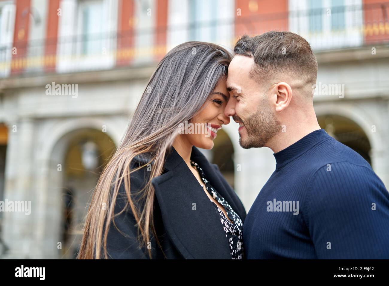 Side view of positive couple in outerwear caressing while standing ...