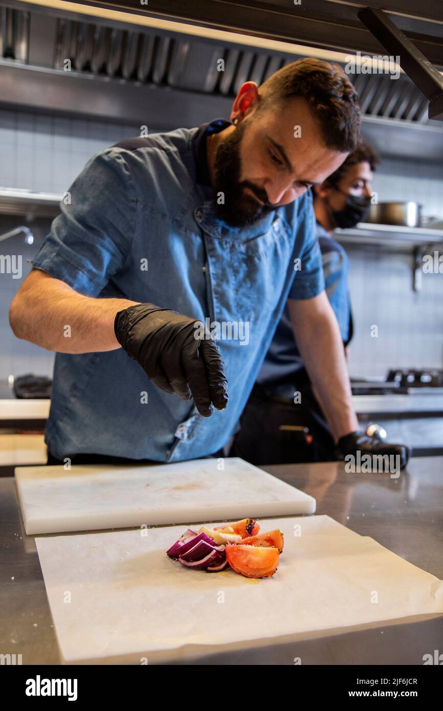 Chef sprinkling seasoning on food at counter in commercial kitchen ...