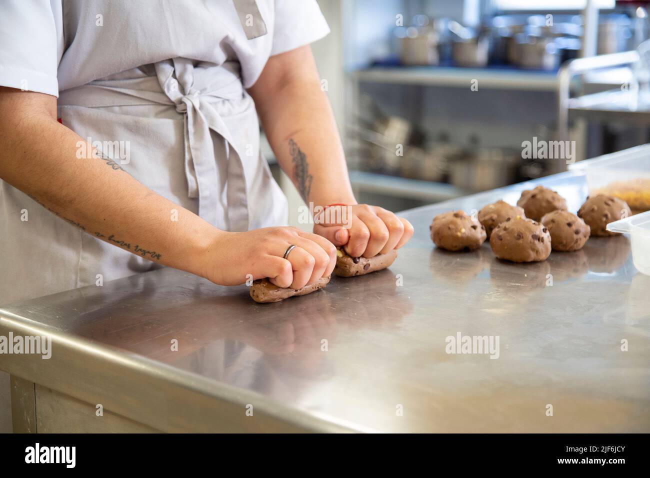 Anonymous side view of female baker in workwear dividing dough for ...