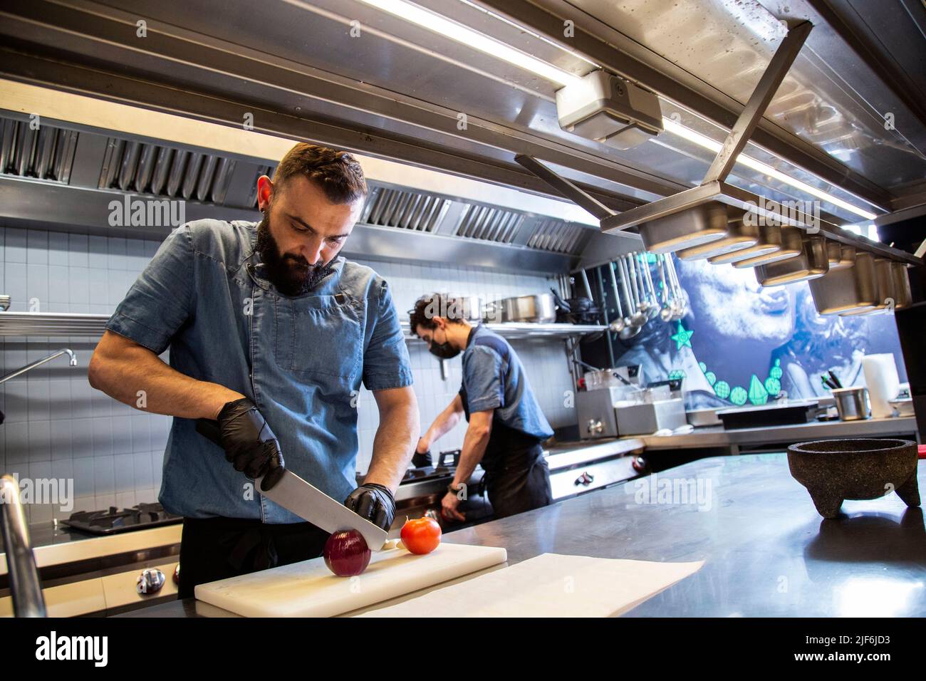 Male chef slicing onion and tomato on cutting board in restaurant Stock ...
