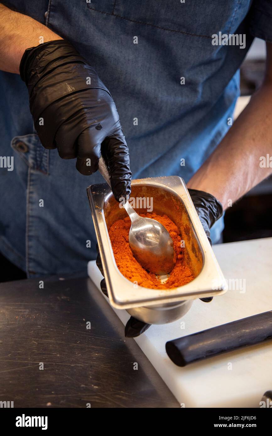 Crop male chef taking with teaspoon spices ground red pepper for ...