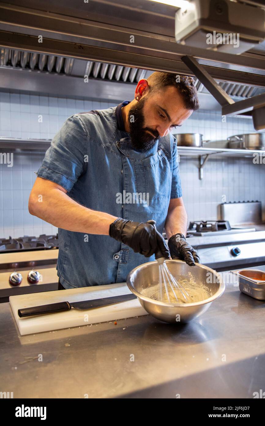 Chef whipping flour in mixing bowl at kitchen counter in restaurant ...
