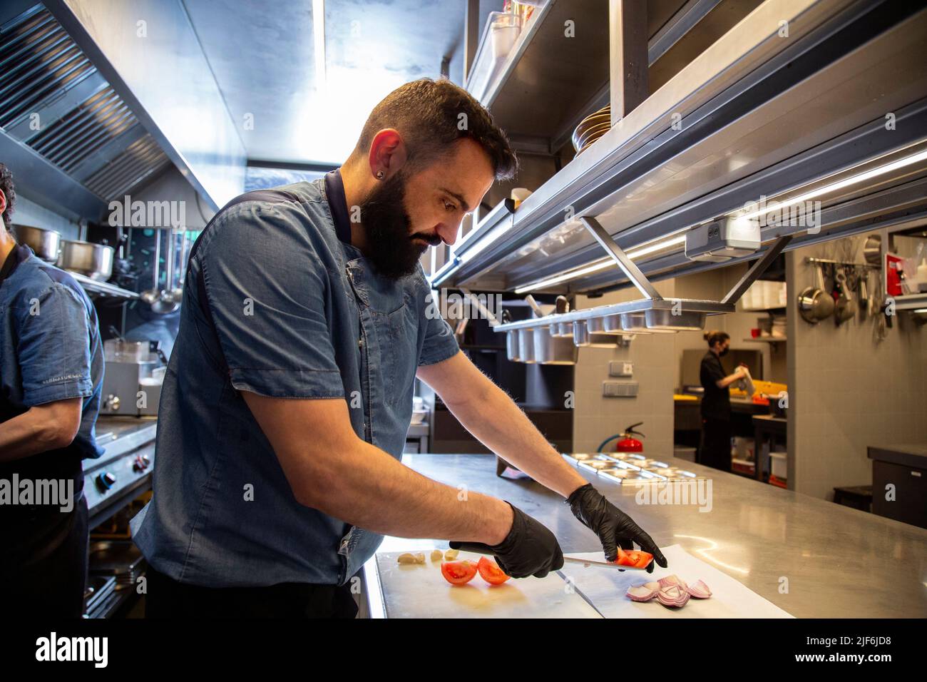 Male chef slicing onion and tomato on cutting board in restaurant Stock ...