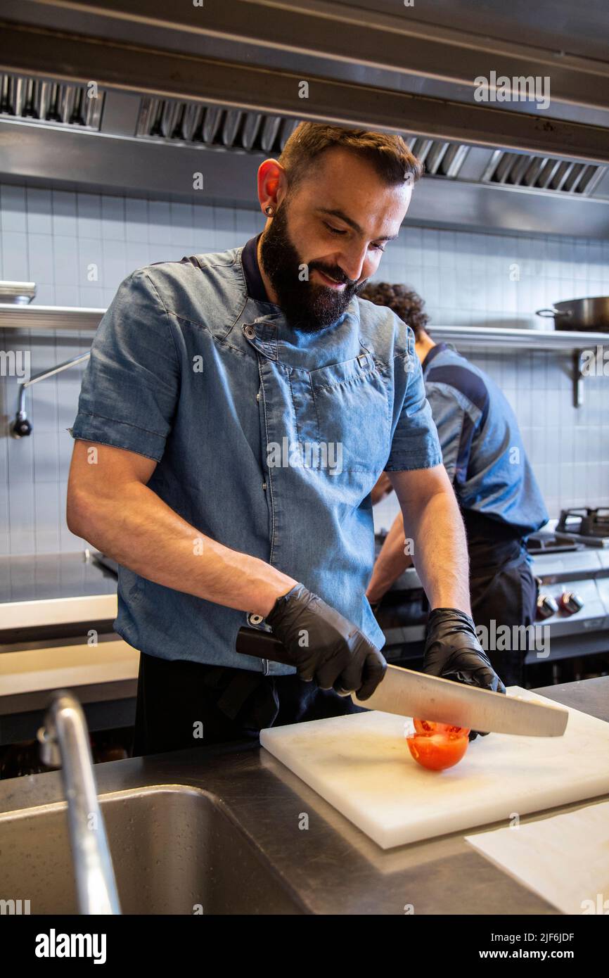 Male chef slicing tomato on cutting board in restaurant Stock Photo - Alamy