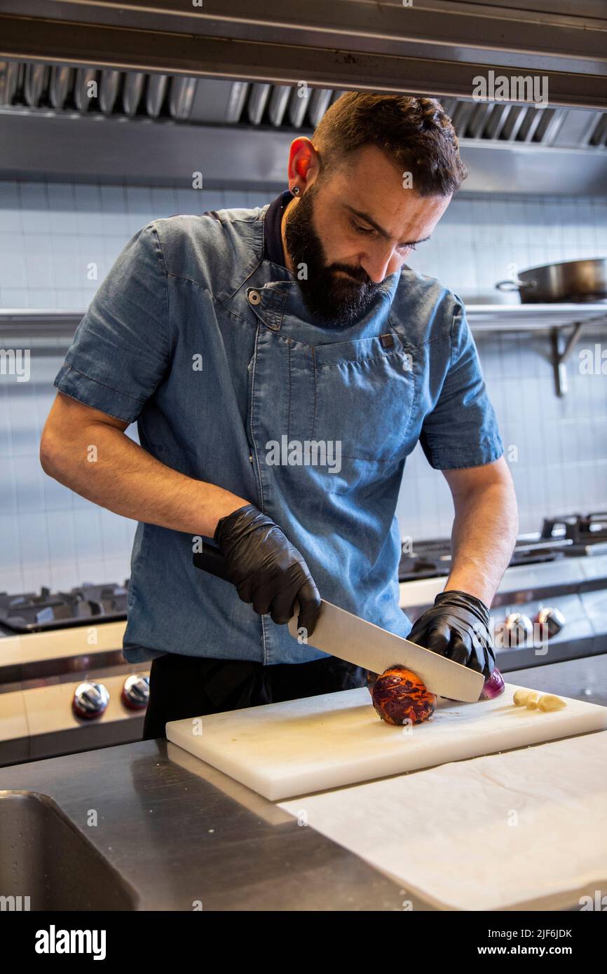 Male chef slicing onion and tomato on cutting board in restaurant Stock ...