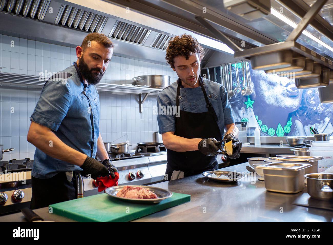 Caucasian chefs preparing dish for customer in commercial kitchen Stock ...