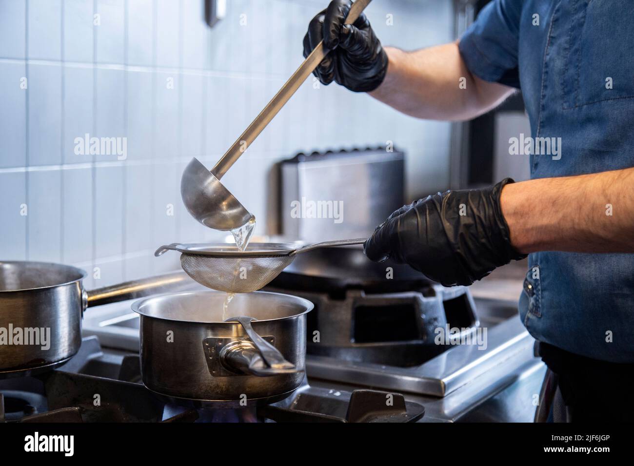 Chef separating water from rice using strainer in commercial kitchen ...