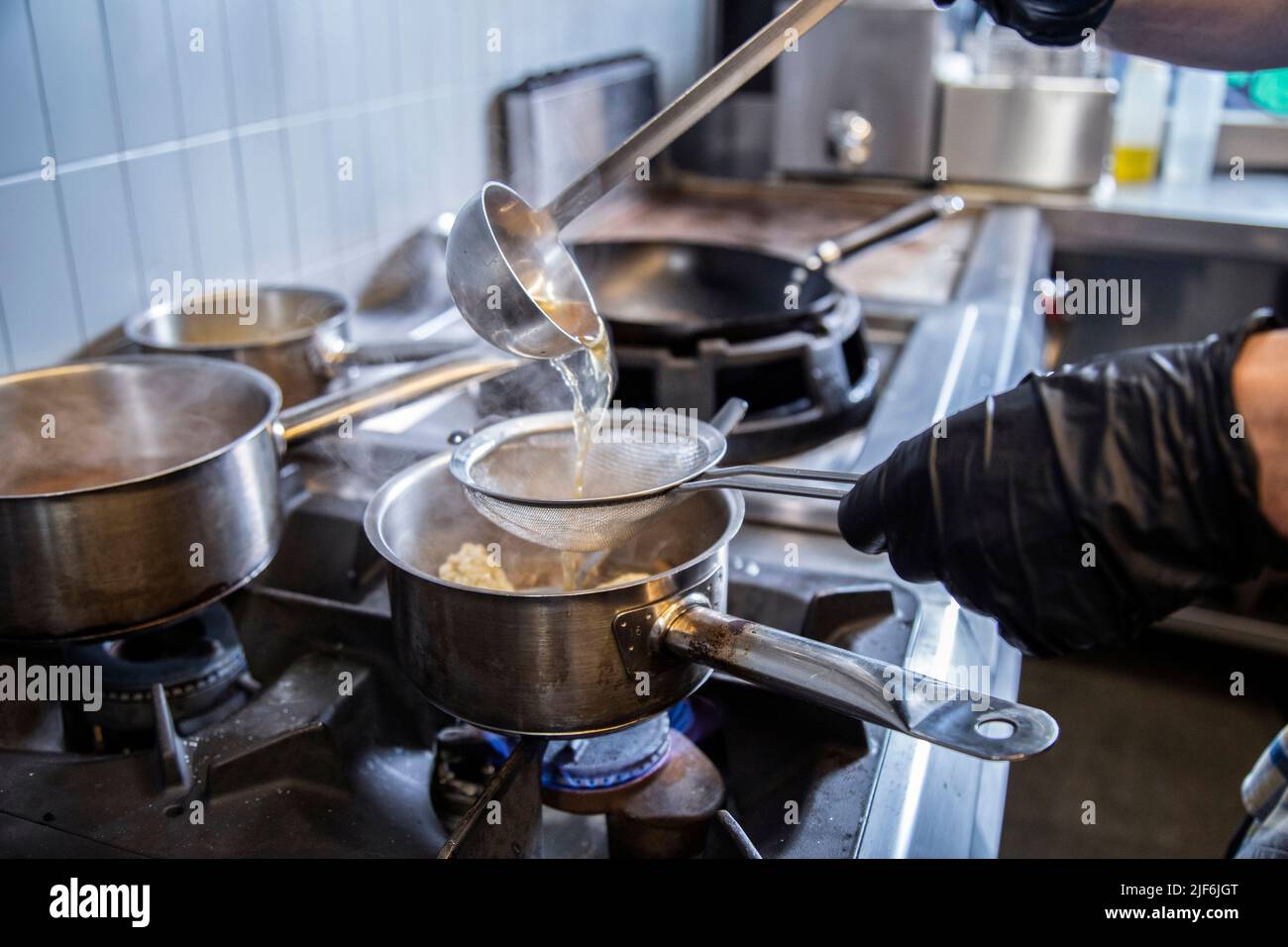 Chef separating water from rice using strainer in commercial kitchen ...