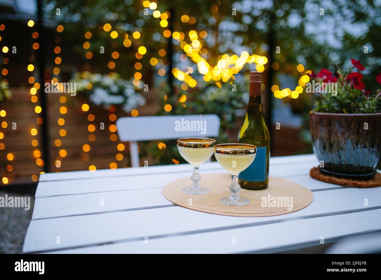 Glasses with champagne served on white wooden table with bottle on ...