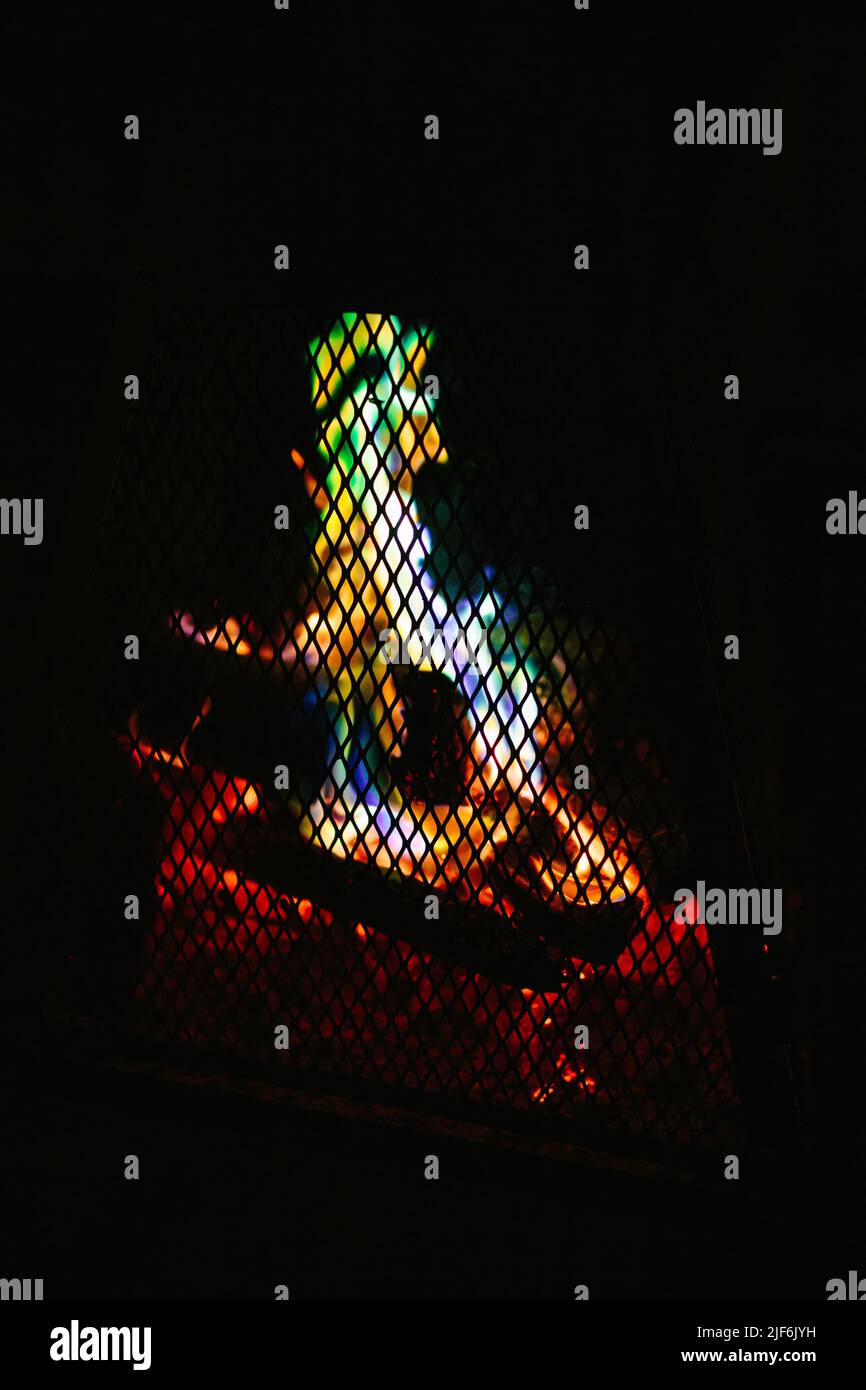 Fireplace with black metal mash and hot burning heap of firewood with ...