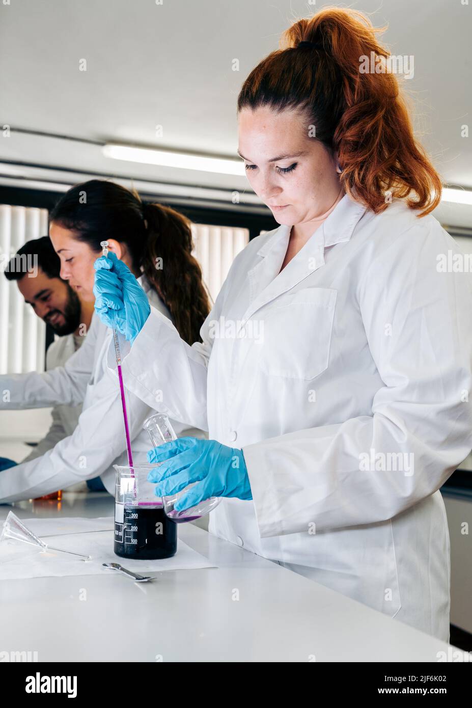 Concentrated female scientist in medical uniform standing near ...