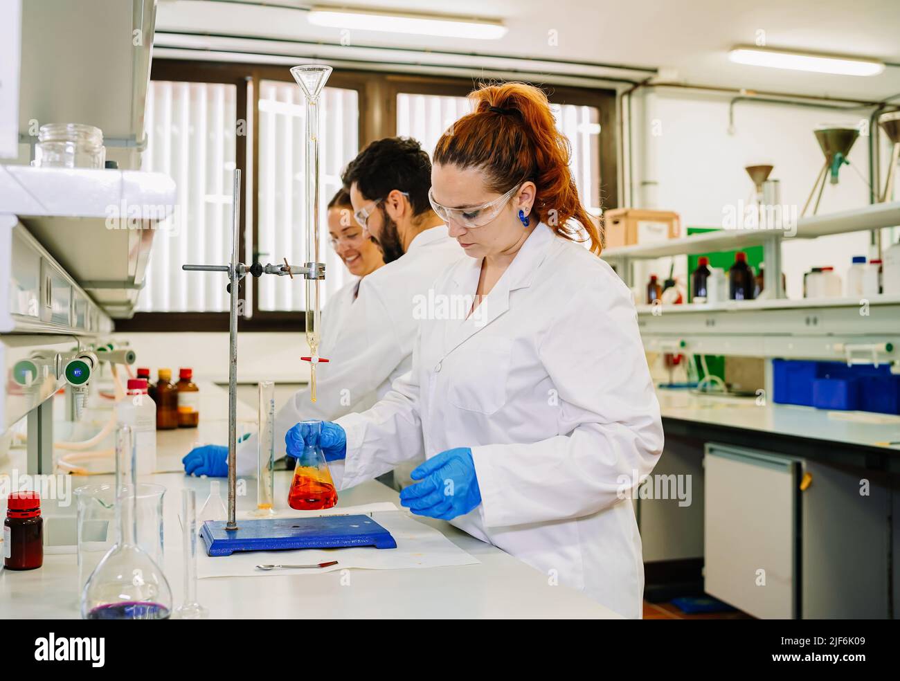 Side view of group of chemists in white uniform and protective glasses ...