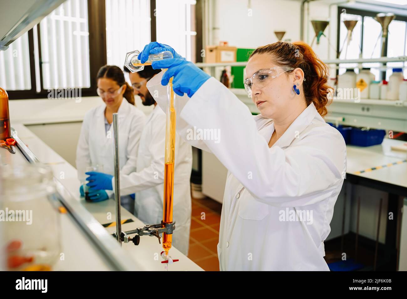 Side view of concentrated chemists in white uniforms and protective ...