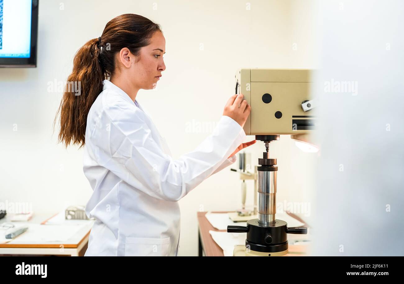 Side view of serious female scientist in medical robe setting up modern ...