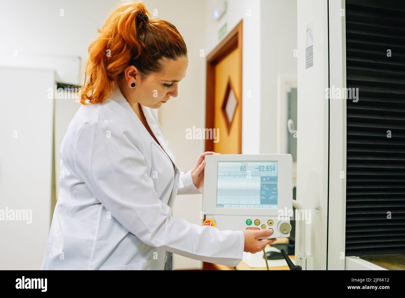 Serious female scientist pressing button of modern electronic machine ...