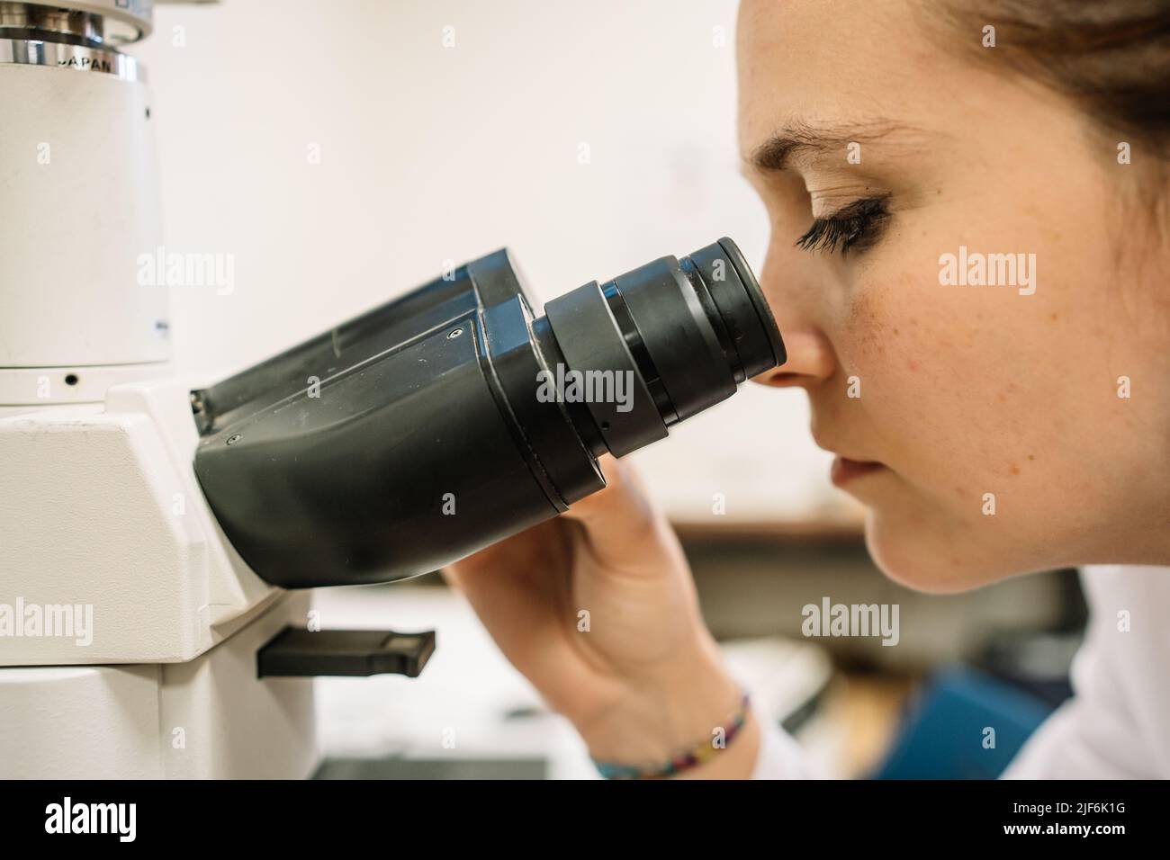 Side view of concentrated female scientist in white medical uniform ...