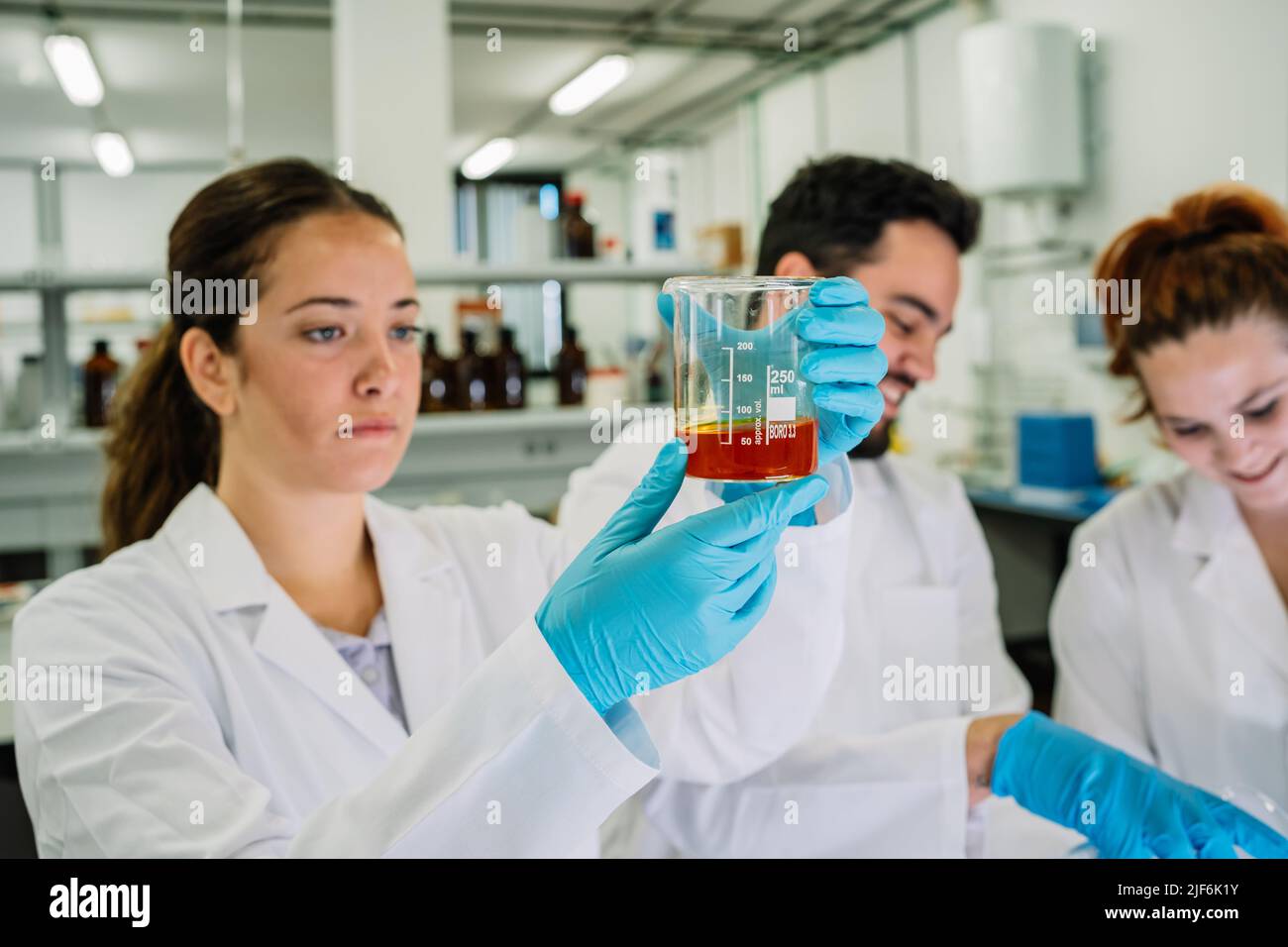 Focused female scientist in protective glasses and latex gloves ...