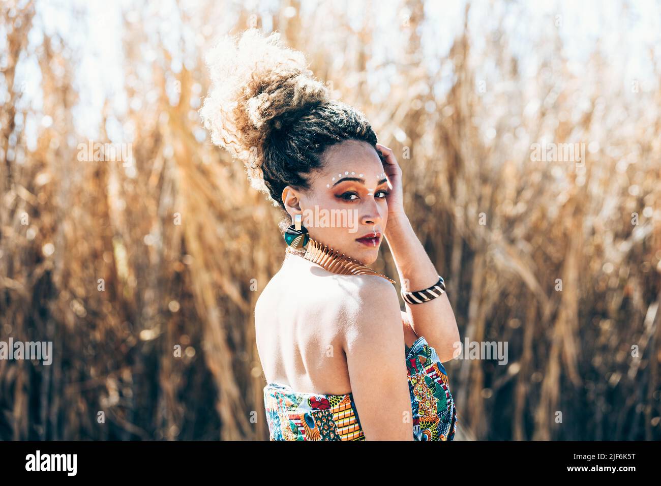 Mixed race female with authentic African accessories and makeup raising ...