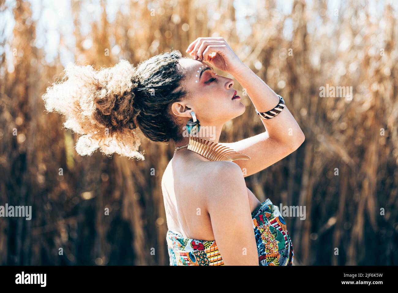 Mixed race female with authentic African accessories and makeup raising ...