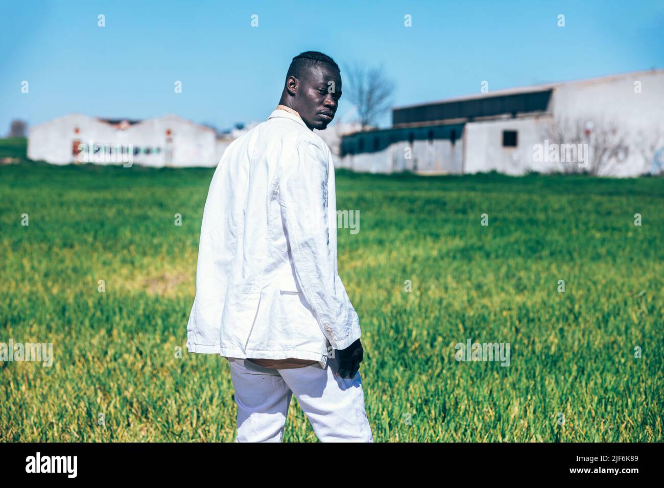 Serious black male model in trendy white suit and authentic African ...
