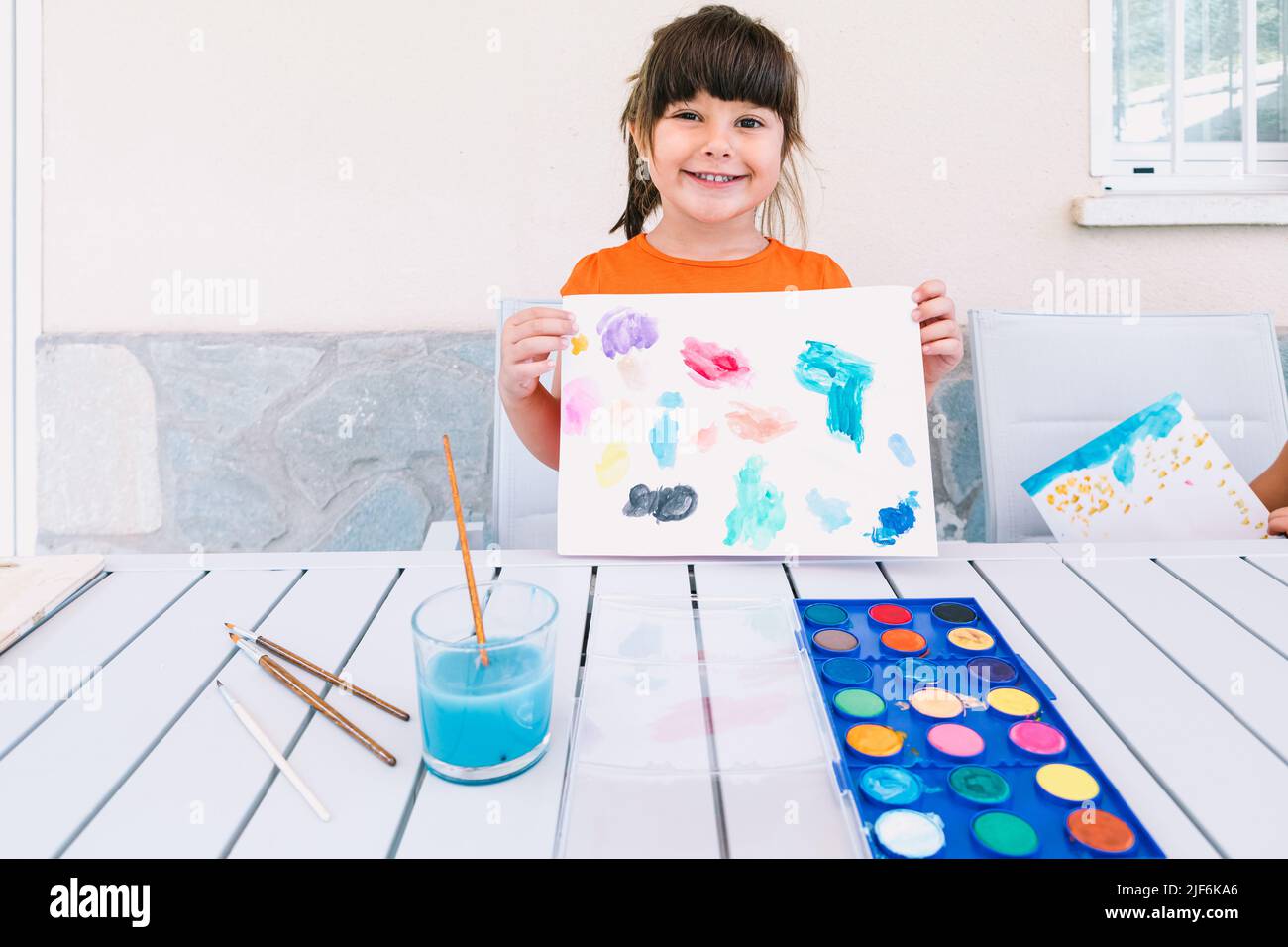 Positive girl looking at camera and demonstrating paper with colorful ...
