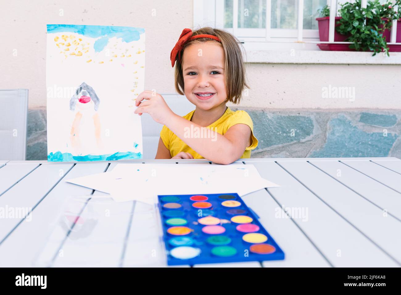Positive girl looking at camera and demonstrating paper with colorful ...