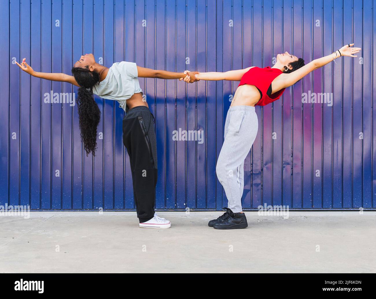 Full body side view of active diverse female dancer holding hands and ...