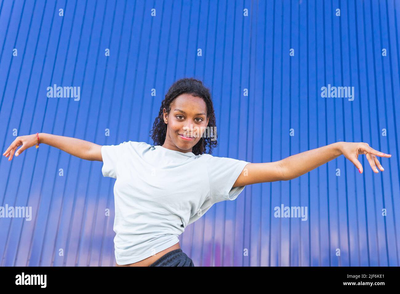 From below female dancer standing next to on blue wall with ...