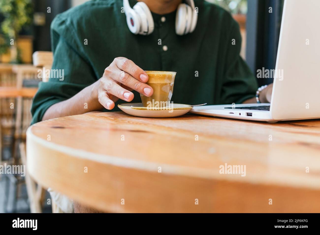 Anonymous ethnic male freelancer drinking coffee while working remotely ...