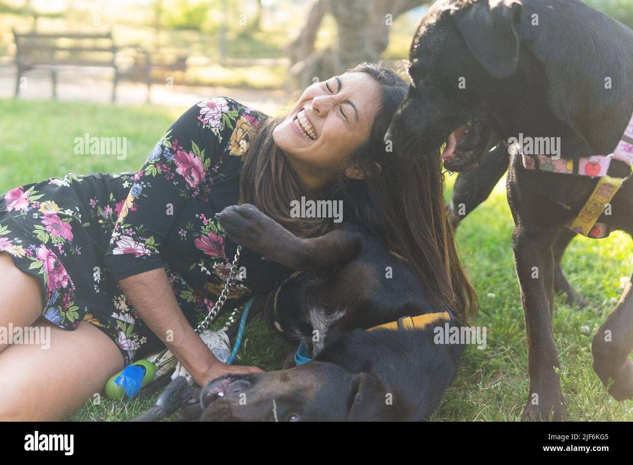 Excited female owner laughing with closed eyes while resting on lawn ...