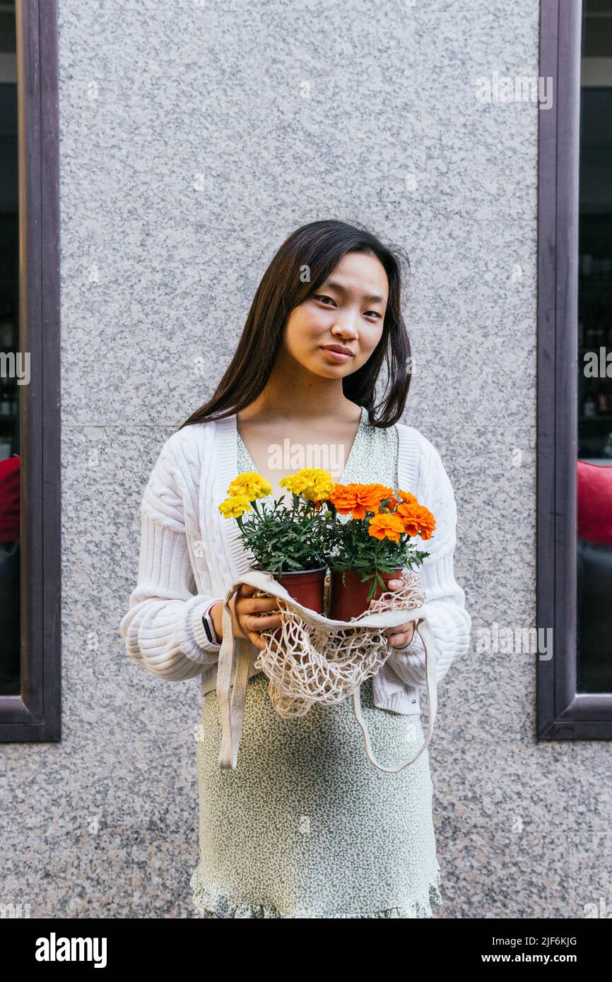 Charming Asian female customer carrying potted colorful marigold ...