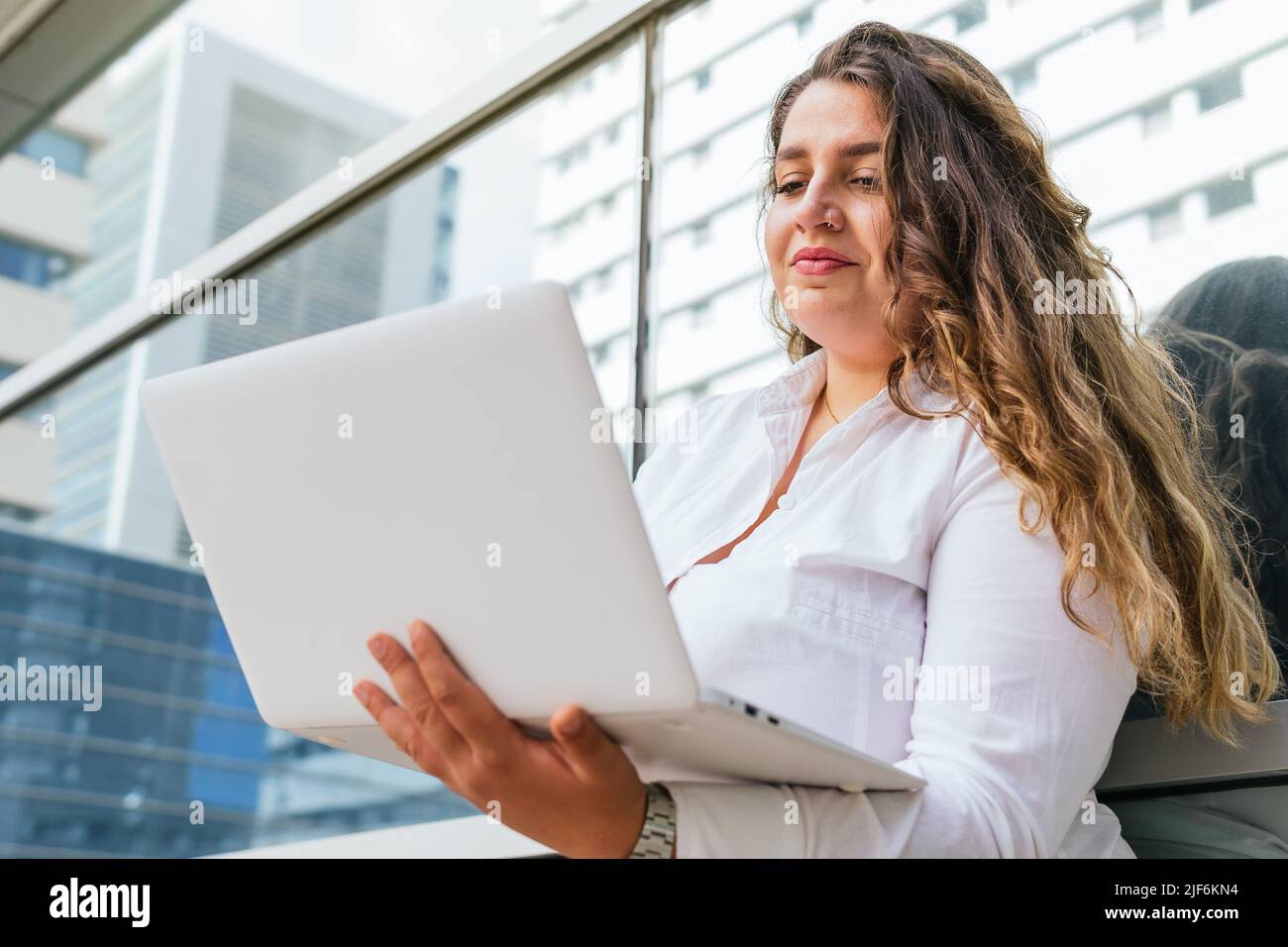Content female freelancer with curly hair typing on white netbook while ...