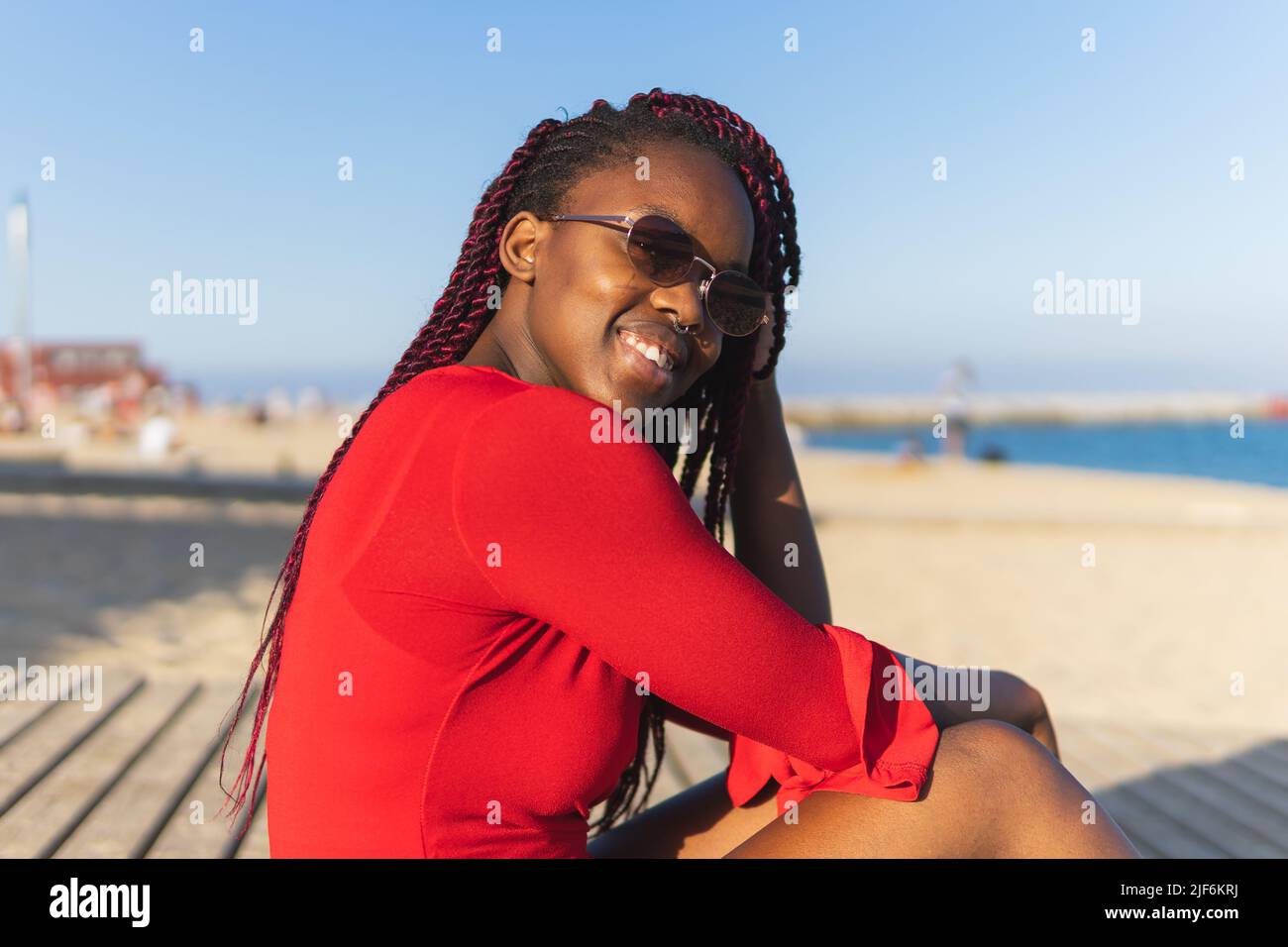 Portrait of African American young Woman in trendy red dress and braids ...