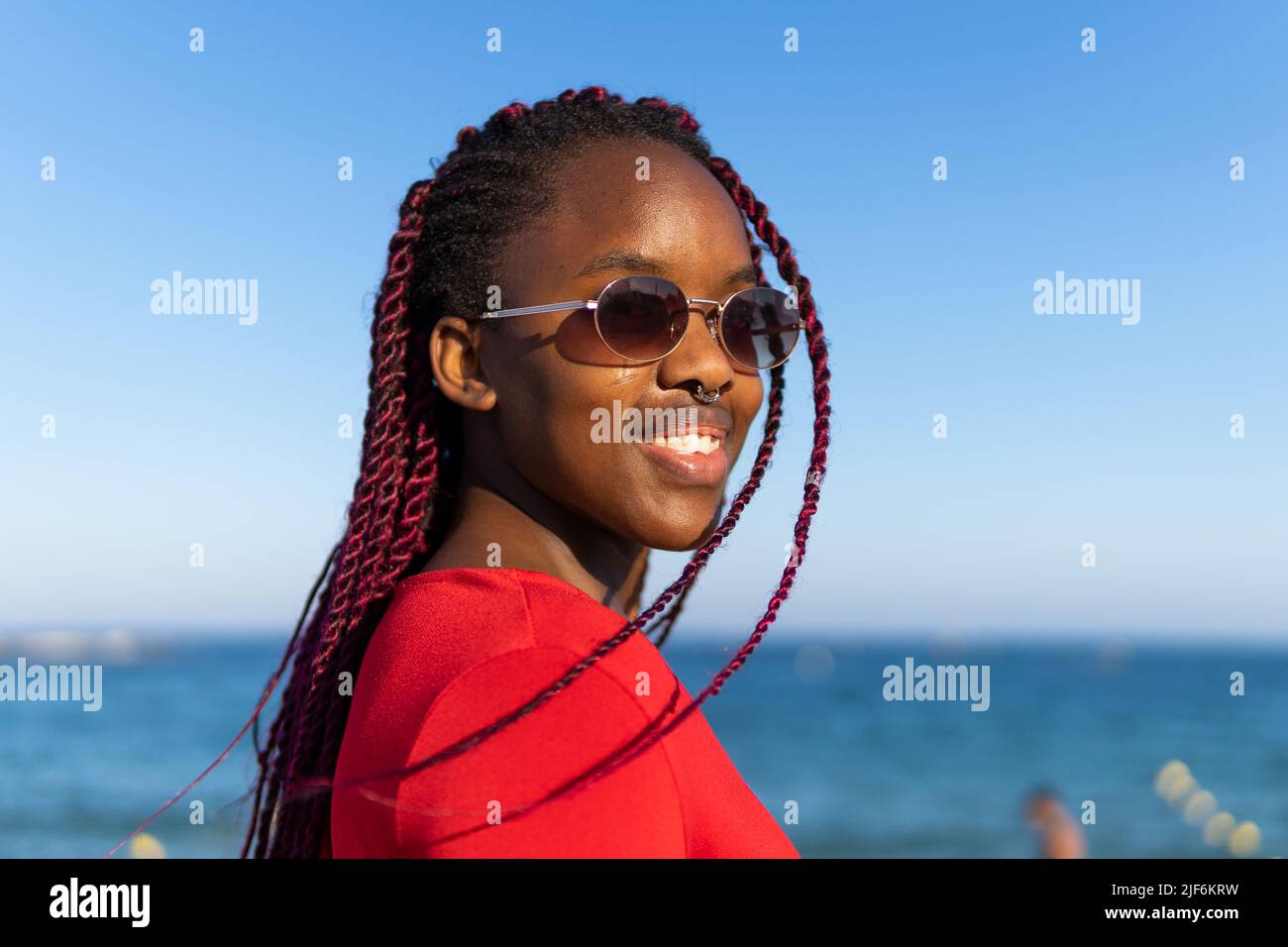 Portrait of African American young Woman in trendy red dress and braids ...
