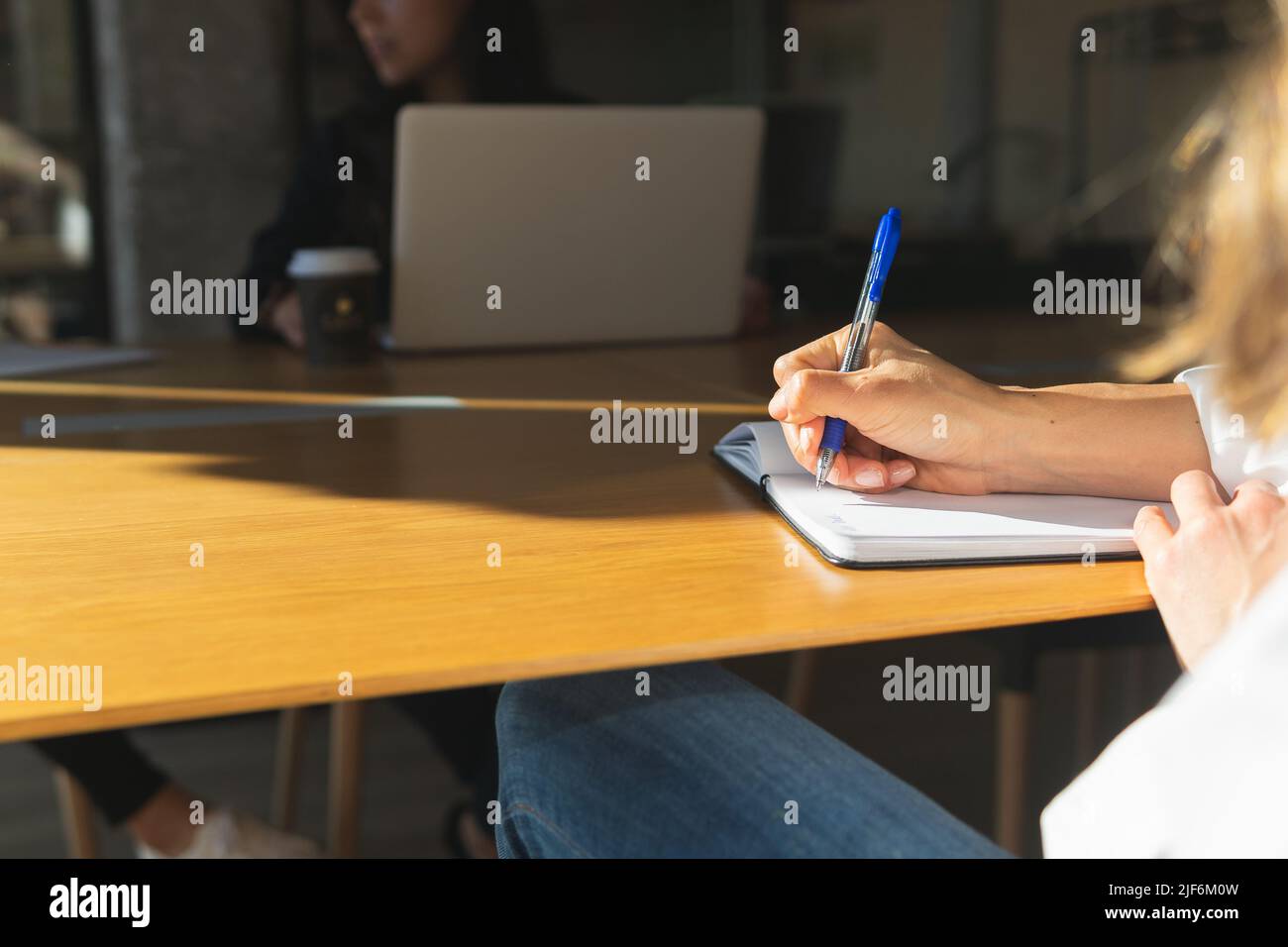Unrecognizable female manager writing in planner while sitting at table ...